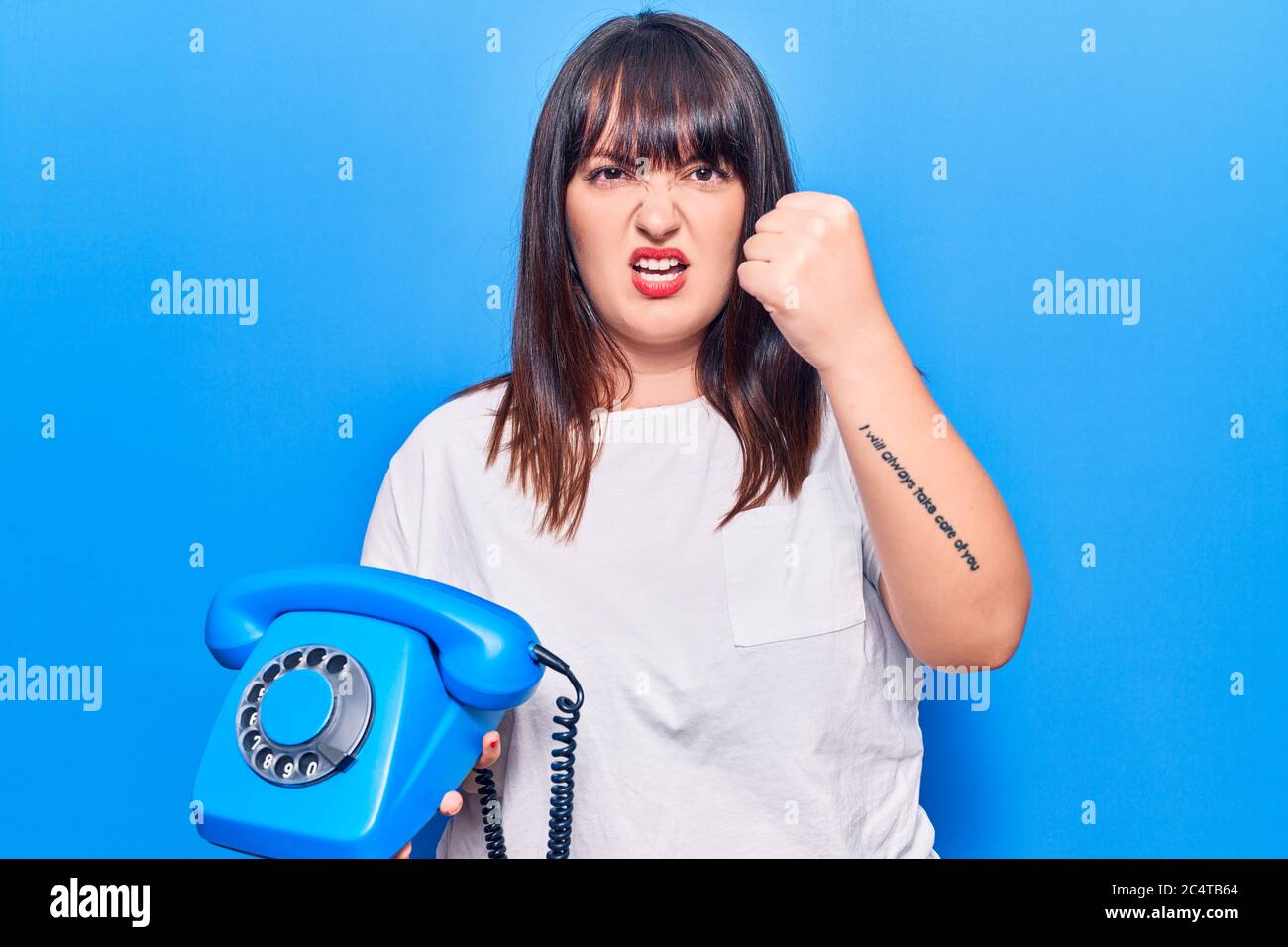 Young plus size woman holding vintage telephone annoyed and frustrated ...