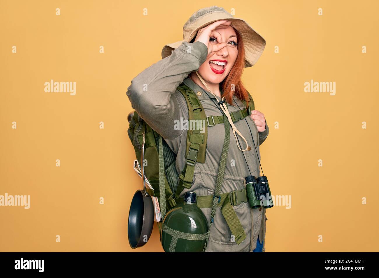 Young redhead backpacker woman hiking wearing backpack and hat over ...