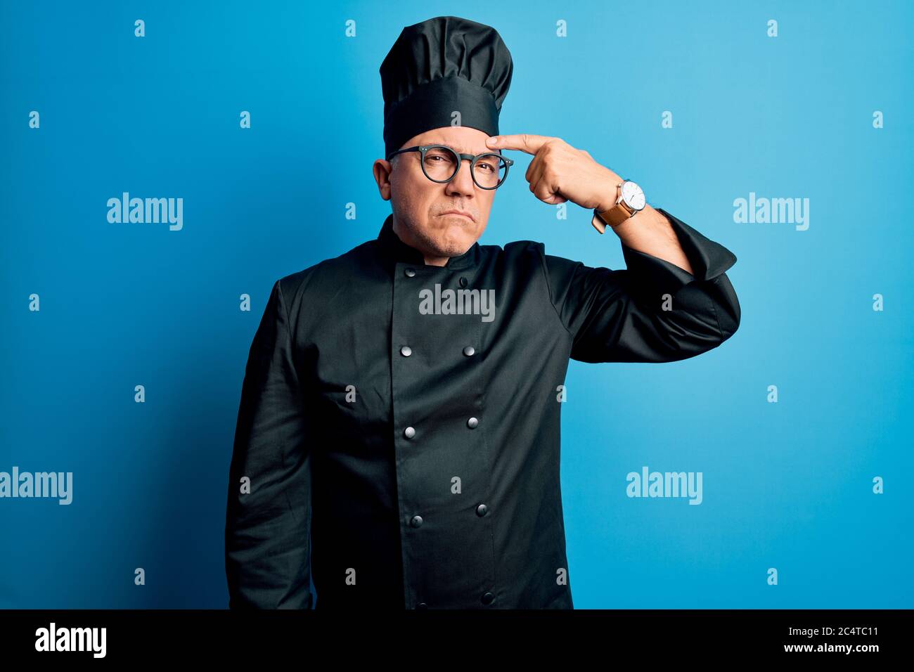 Middle age handsome grey-haired chef man wearing cooker uniform and hat ...