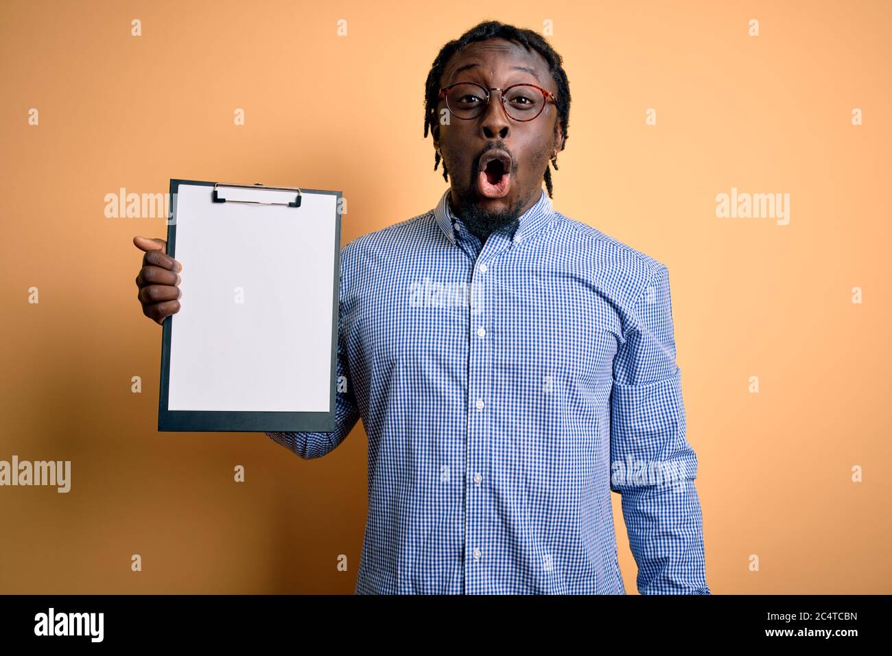 Young african american inspector man wearing glasses holding clipboard ...