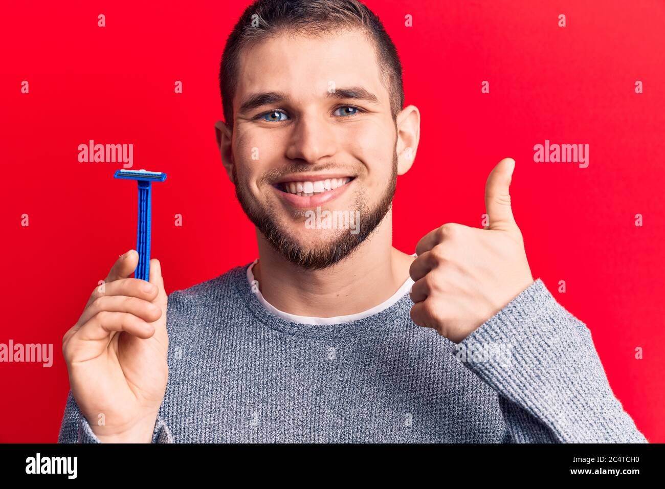 Young handsome man holding shave razor smiling happy and positive ...