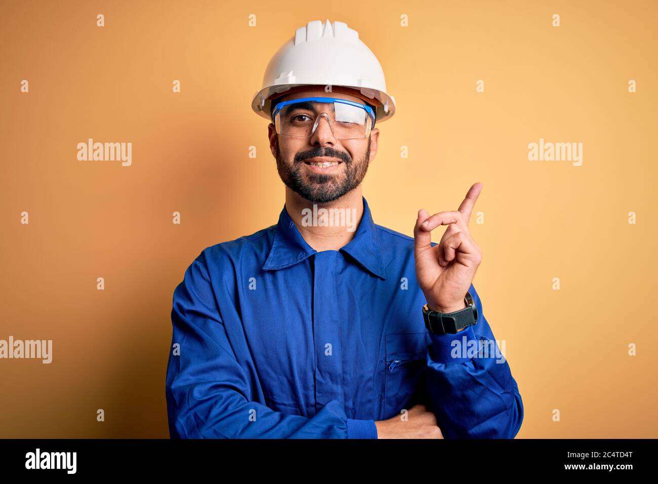 Mechanic man with beard wearing blue uniform and safety glasses over ...