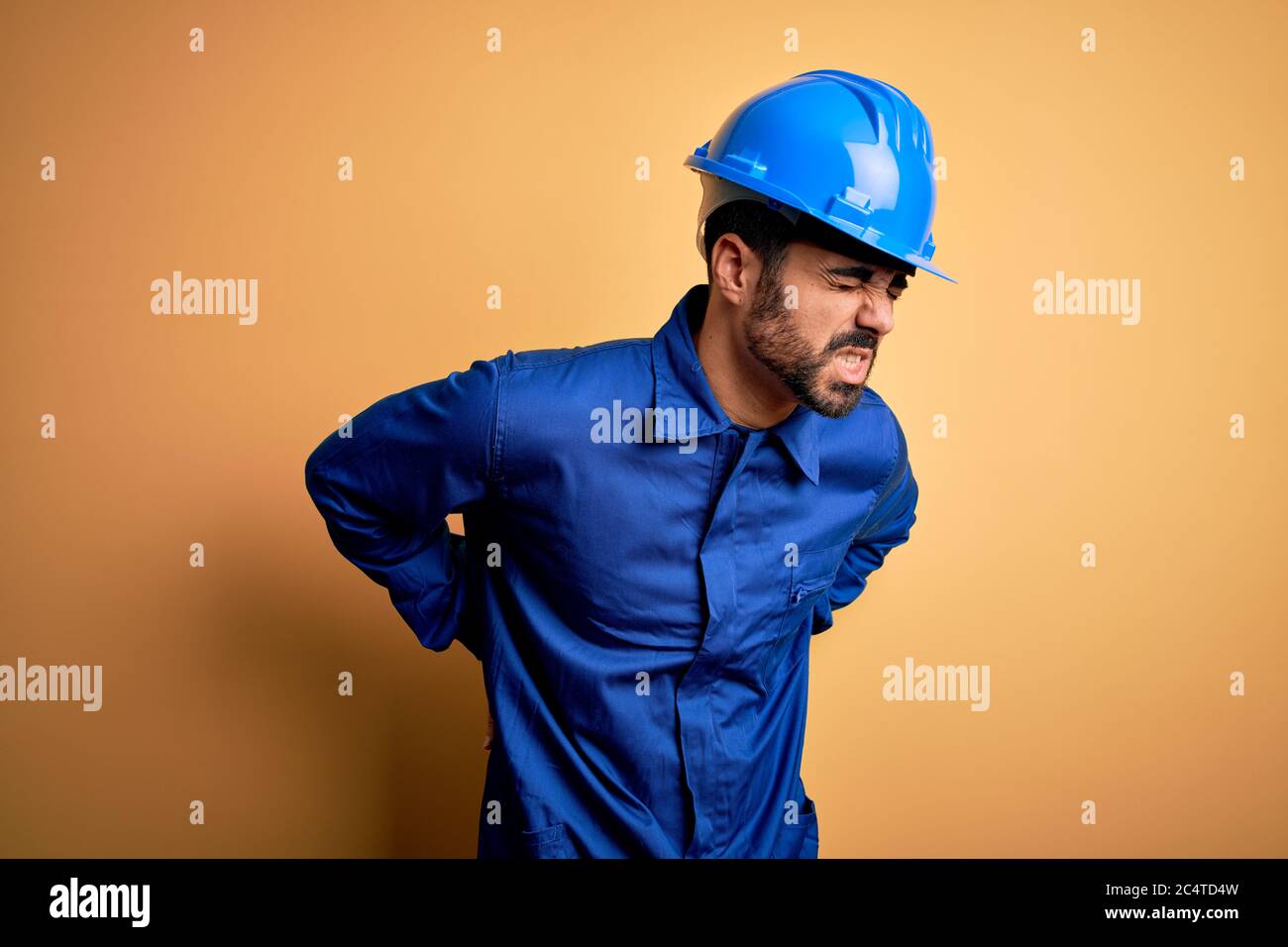 Mechanic man with beard wearing blue uniform and safety helmet over ...