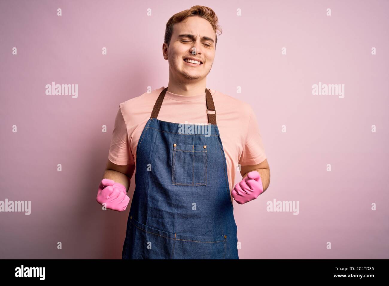 Young Handsome Redhead Cleaner Man Doing Housework Wearing Apron And Gloves Very Happy And