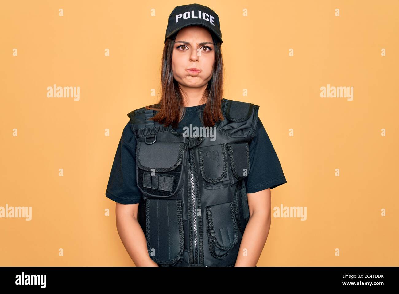 Young beautiful brunette policewoman wearing police uniform bulletproof ...