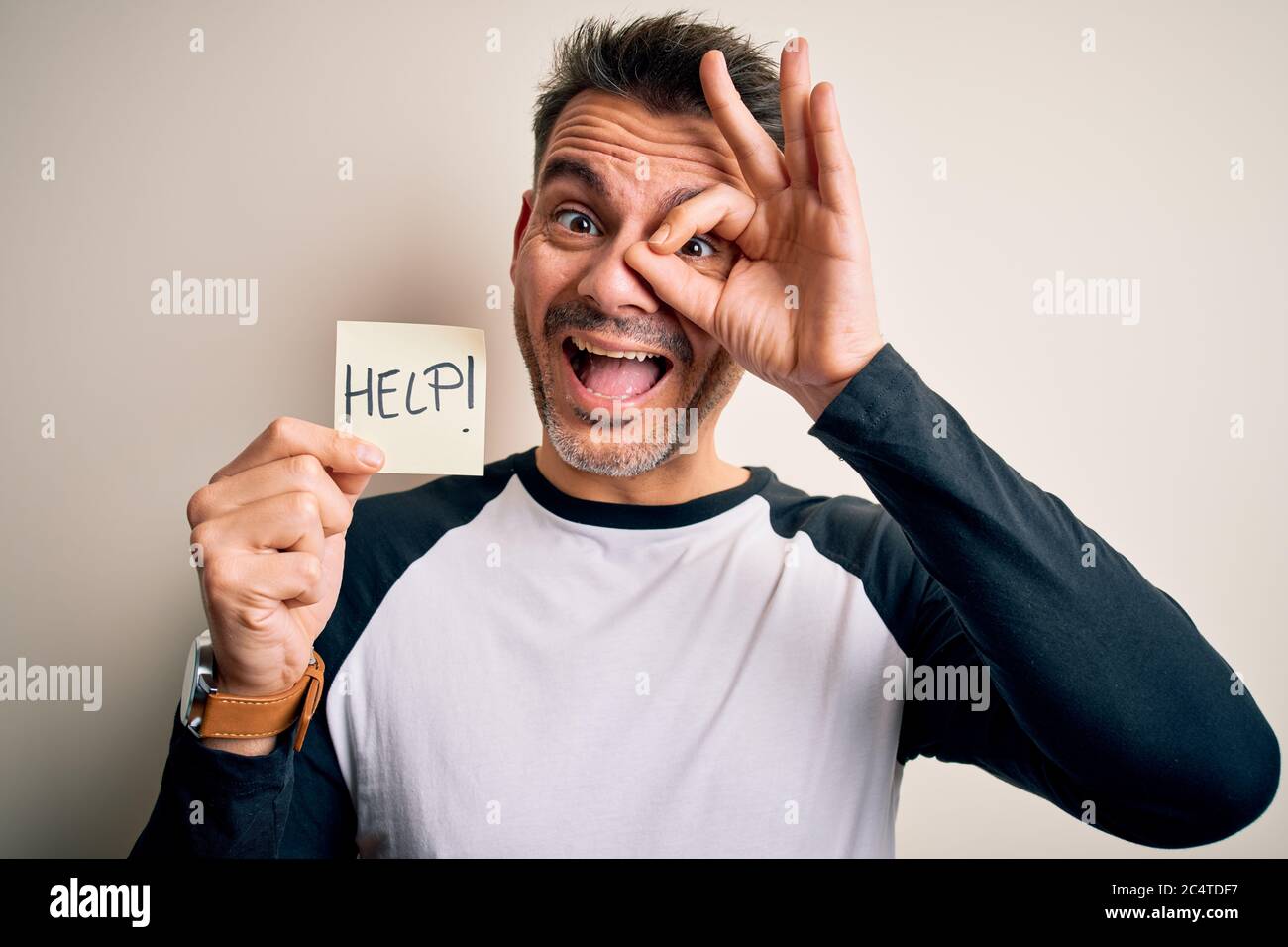 Young handsome man stressed holding reminder paper with help message ...