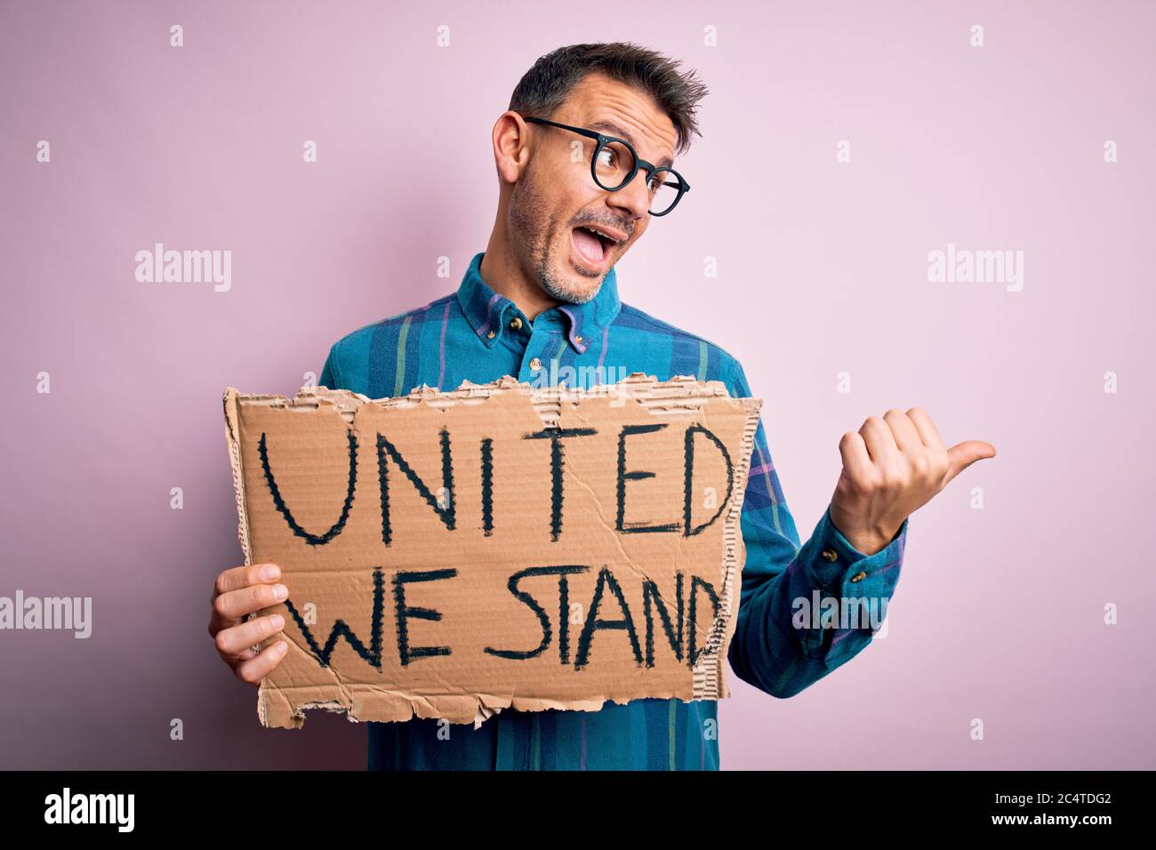 Young handsome activist man asking for union holding banner with united ...