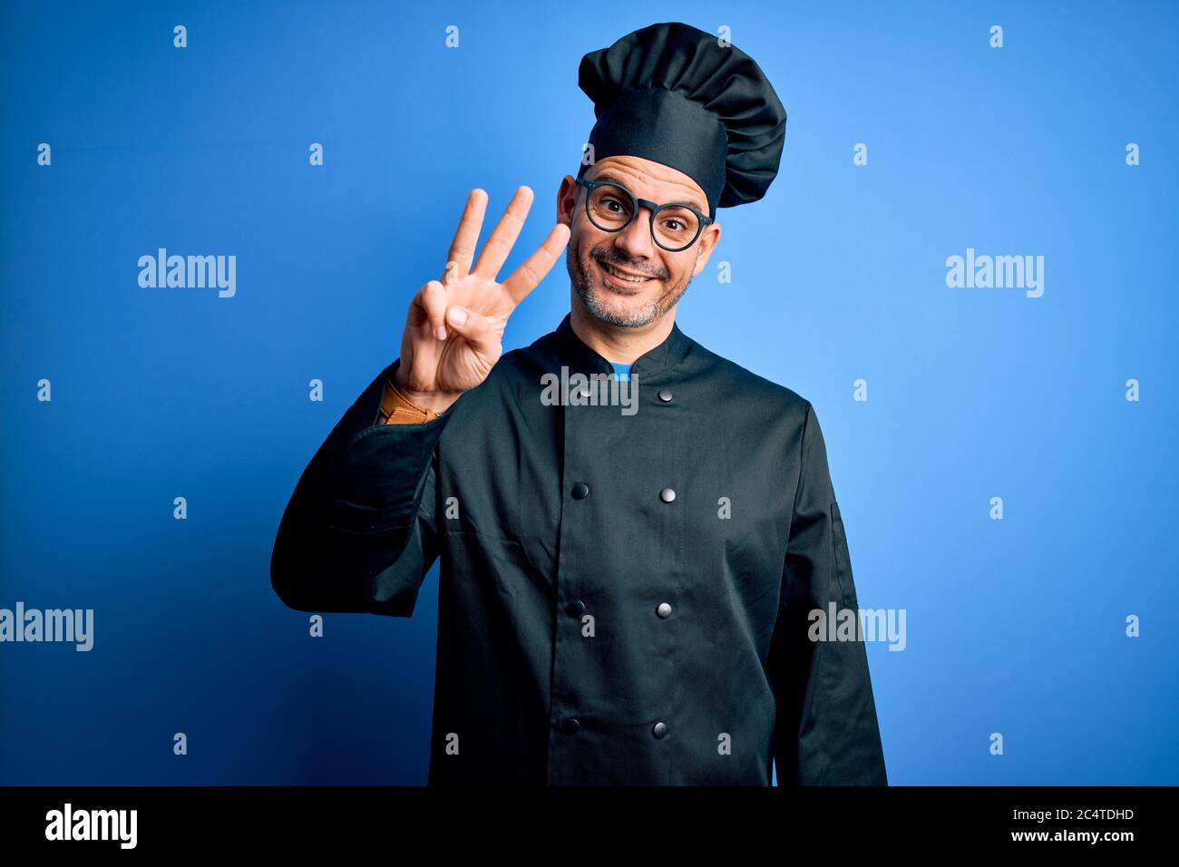 Young handsome chef man wearing cooker uniform and hat over isolated ...