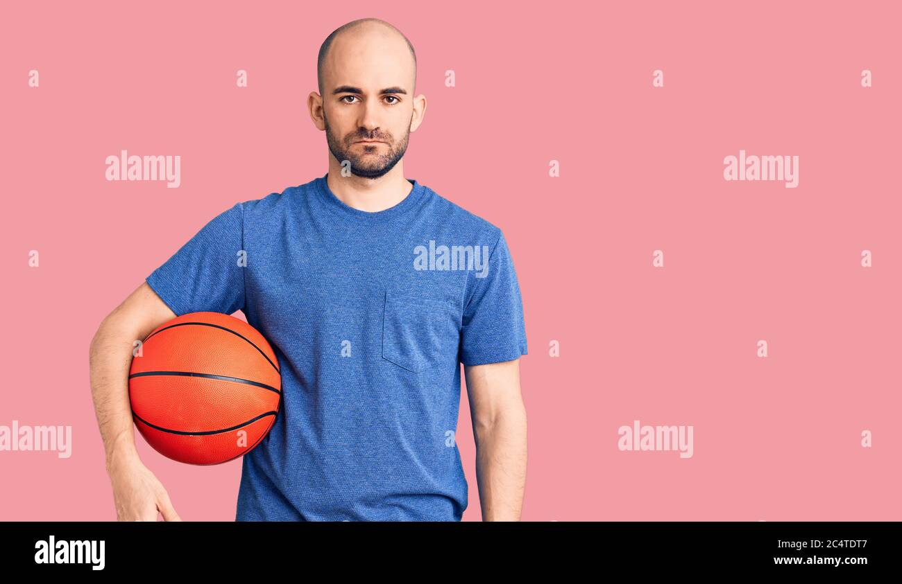 Young handsome man holding basketball ball thinking attitude and sober ...