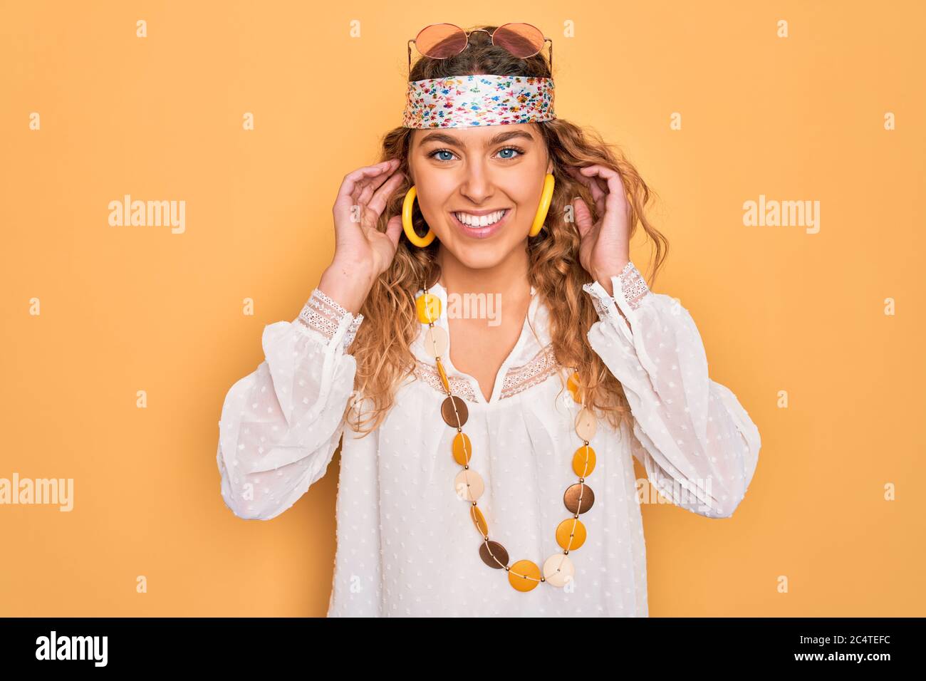 Young beautiful blonde hippie woman with blue eyes wearing sunglasses ...