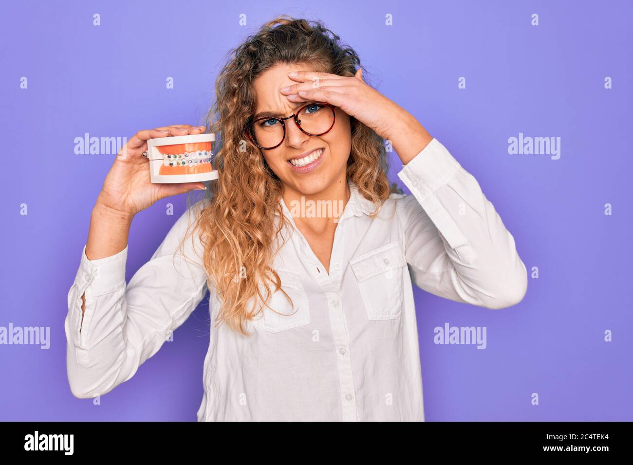 Beautiful blonde woman with blue eyes holding plastic dentrure teeth ...