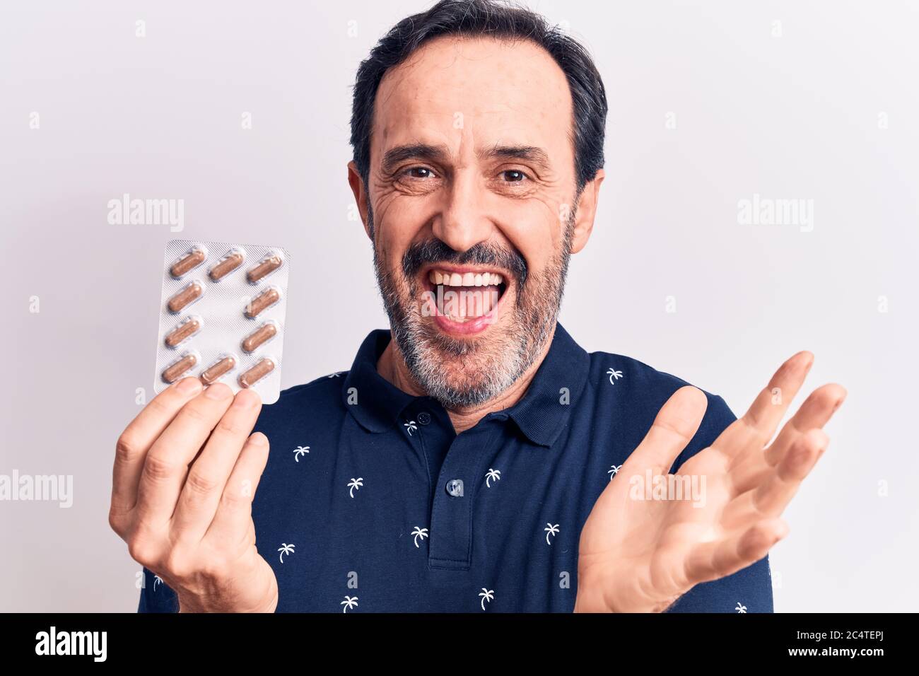 Middle age handsome man holding pills standing over isolated white ...