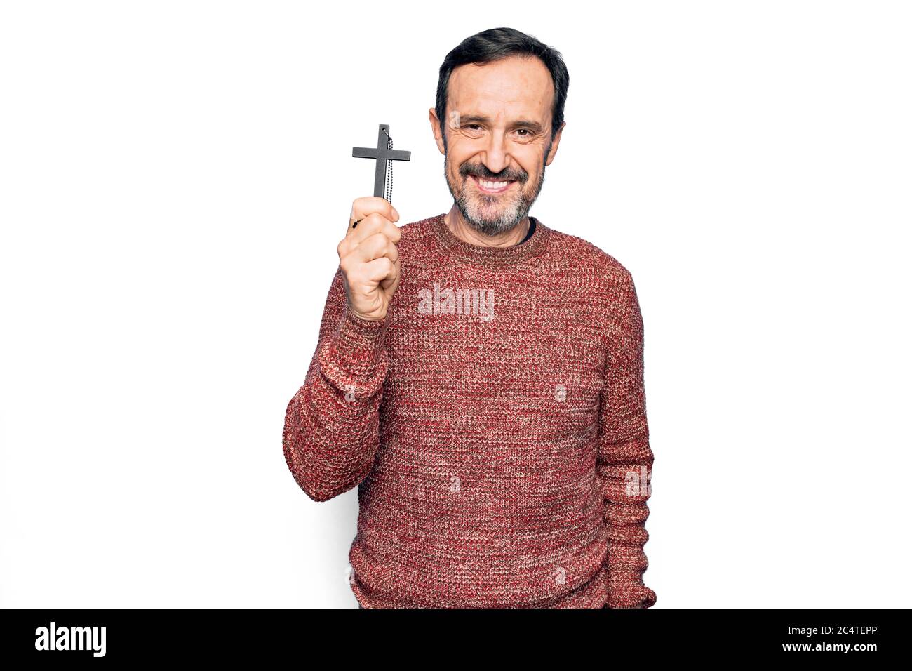 Middle age handsome catholic man praying holding christian cross over ...