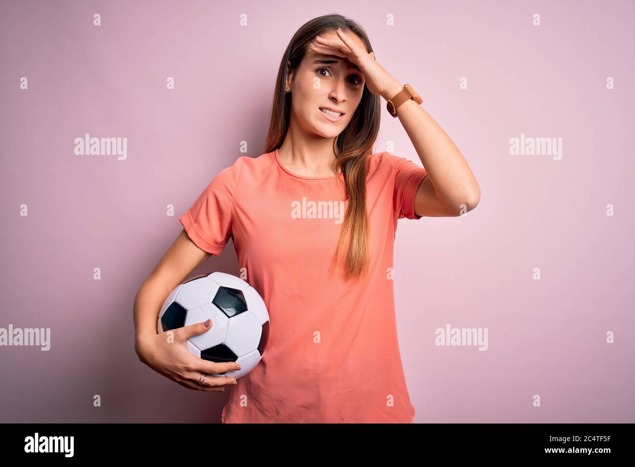 Young beautiful player woman playing soccer holding football ball over ...