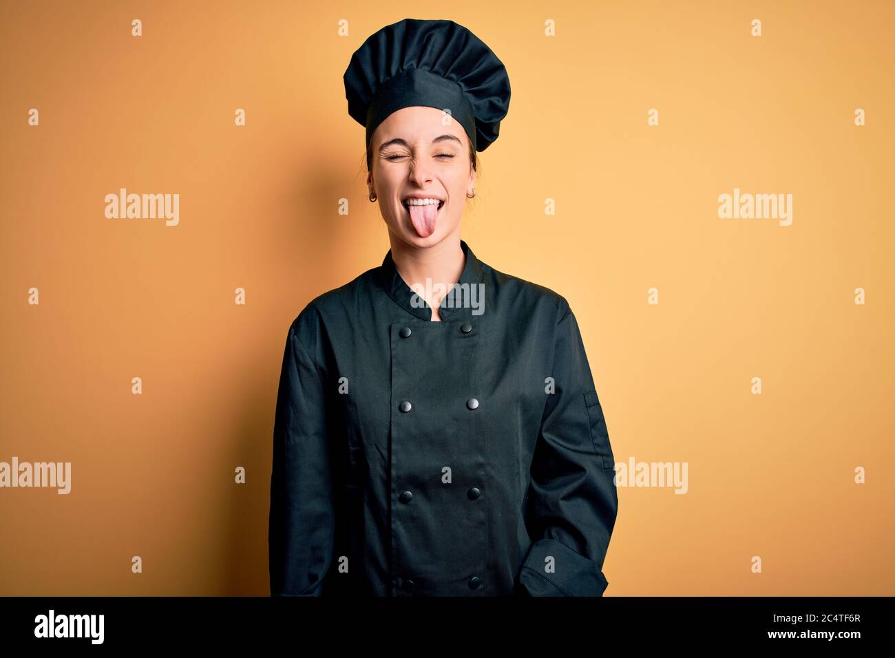 Young beautiful chef woman wearing cooker uniform and hat standing over ...