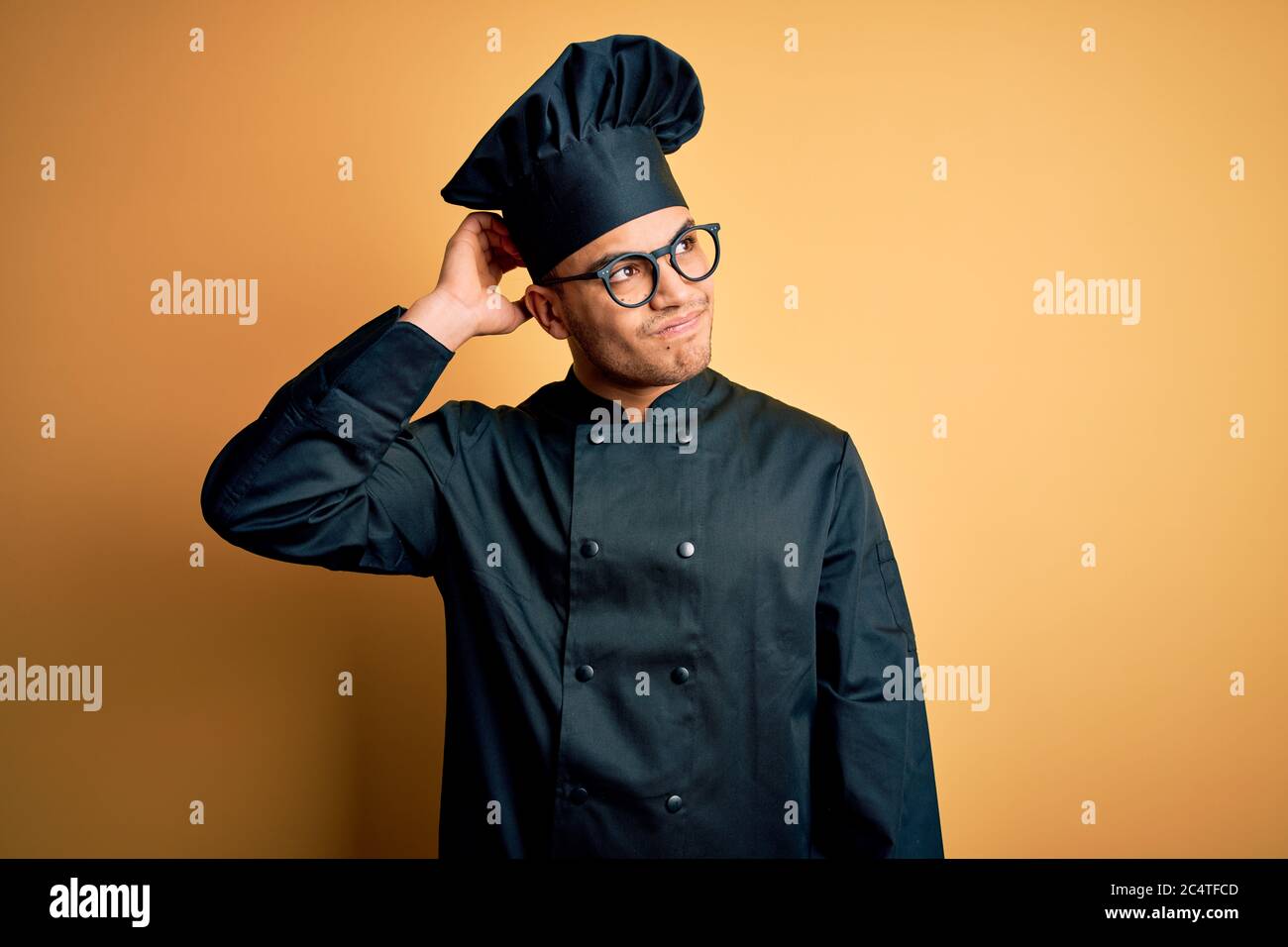 Young brazilian chef man wearing cooker uniform and hat over isolated ...
