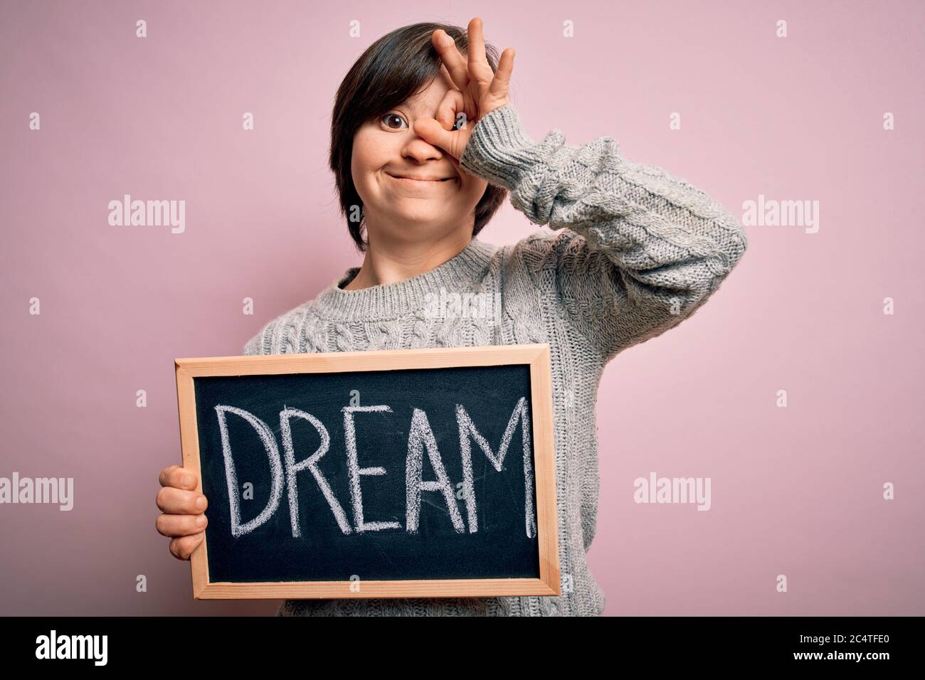 Young down syndrome woman holding blackboard with dream word as message ...