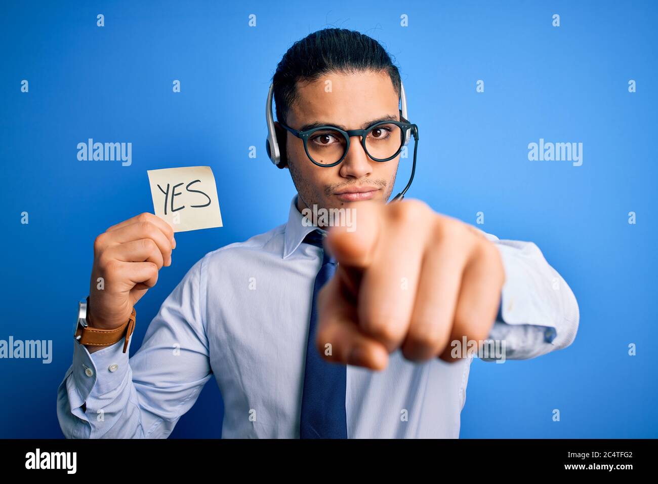 Young brazilian call center agent man holding reminder paper with yes ...