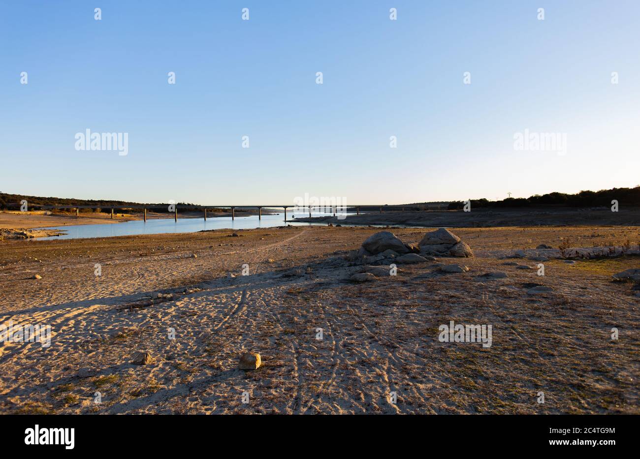 Sandy pathway and the river flowing under the bridge surrounded by ...