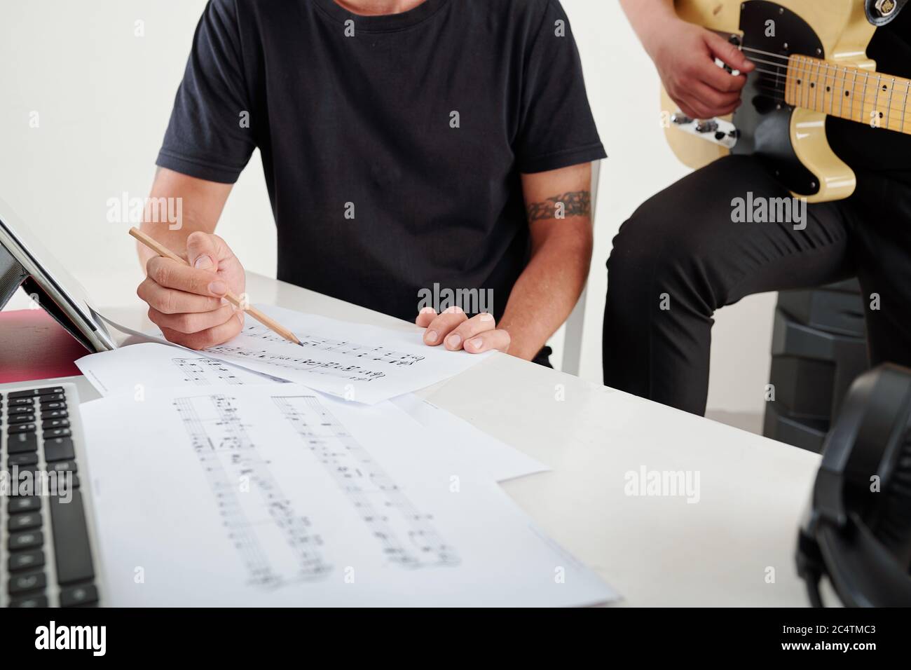 Composers playing guitar and writing musical notes on paper sheets when ...