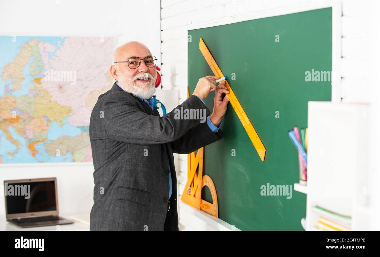 practising time. tutor man in glasses draw with ruler on blackboard ...