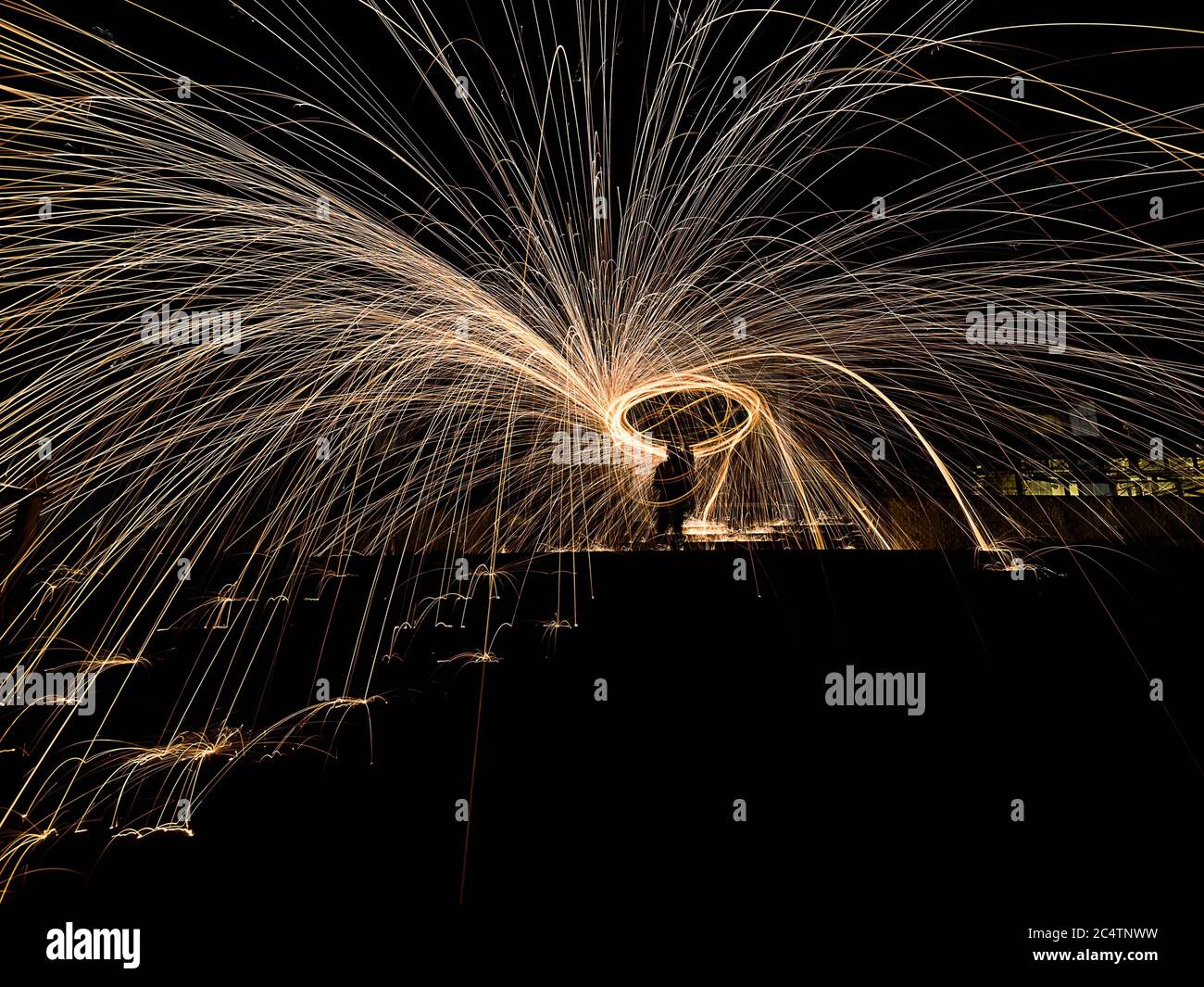 Person standing in the darkness and abstract golden pyro effect lights ...