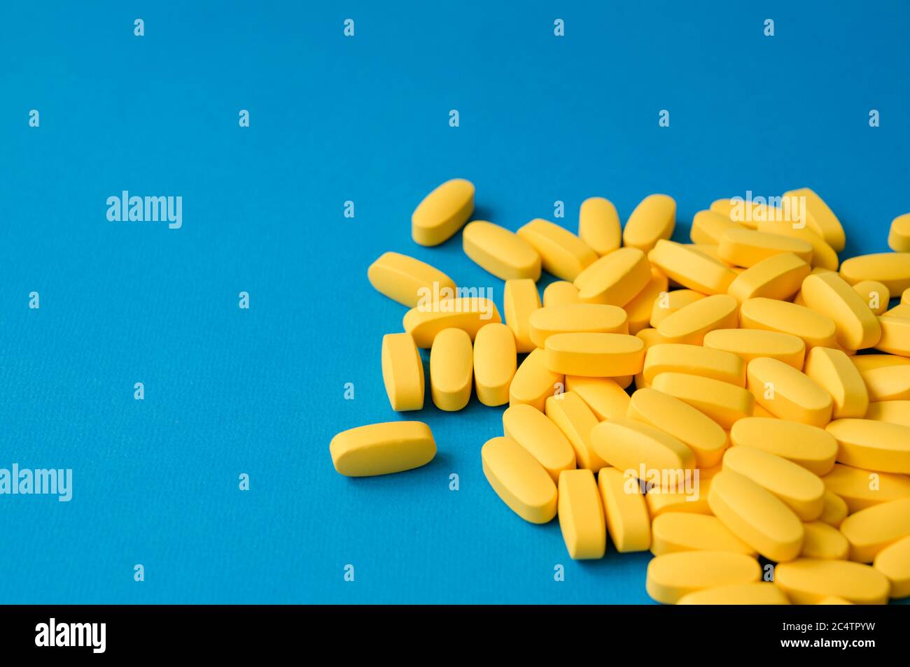 yellow vitamine tablets lying on blue surface Stock Photo - Alamy