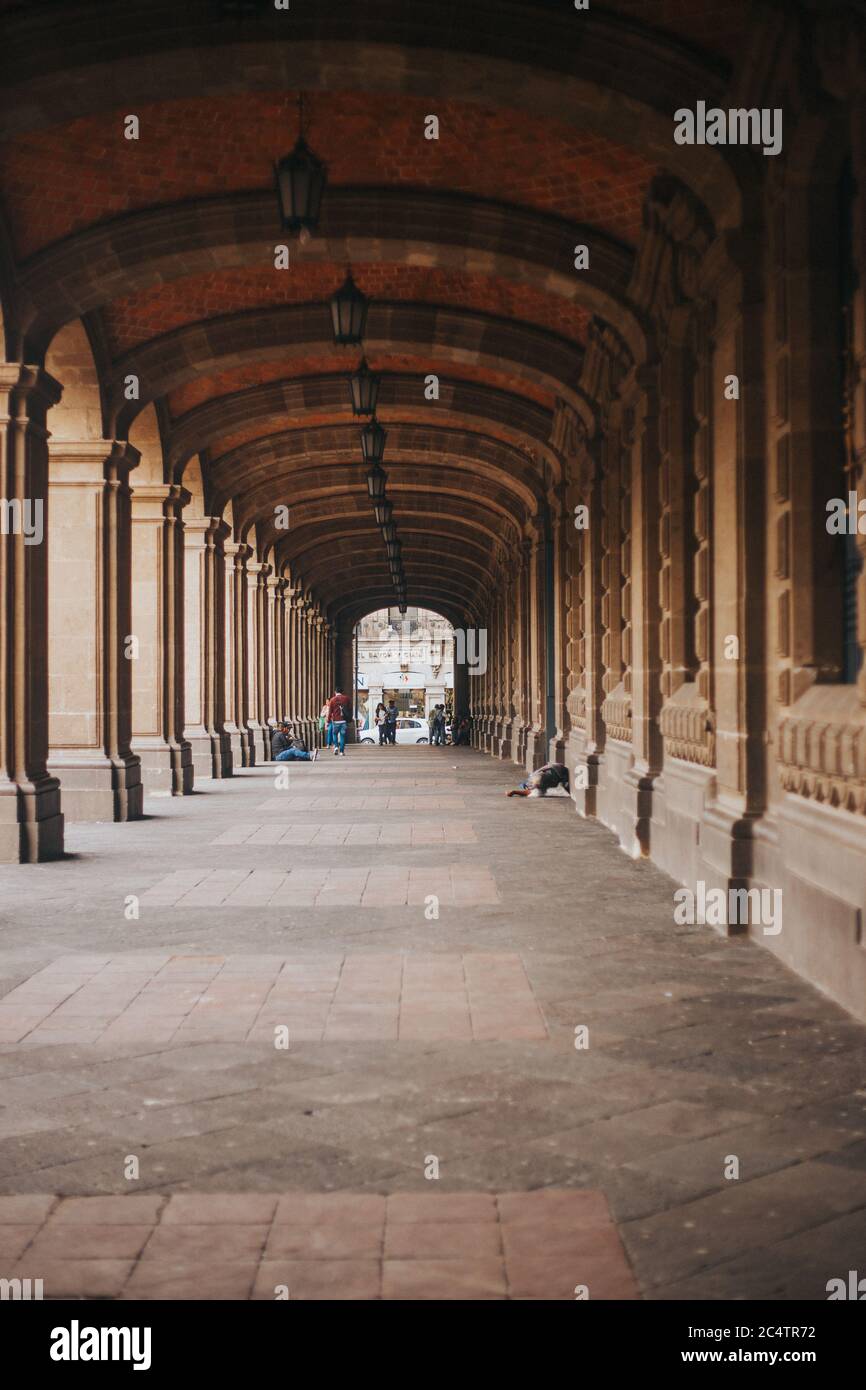 Vertical shot of people in an arc hall in the city with lights on the ...