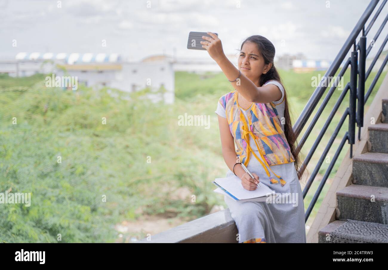 College girl outside home watching online class due to slow internet ...