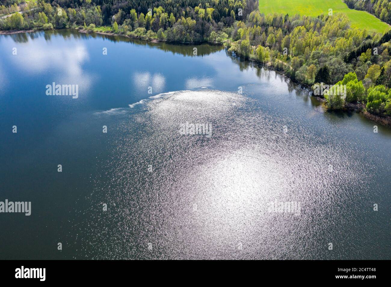 lakeside with colorful trees in spring sunlight and sky reflection at ...