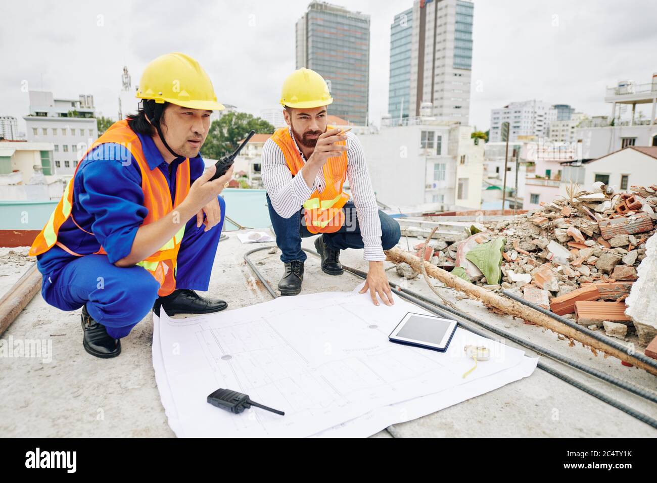 Construction engineer pointing at building wall when contractor using ...