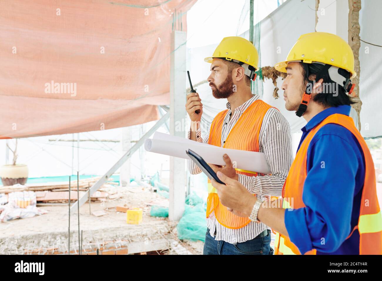Serious construction workers in hardhat controlling process of house ...