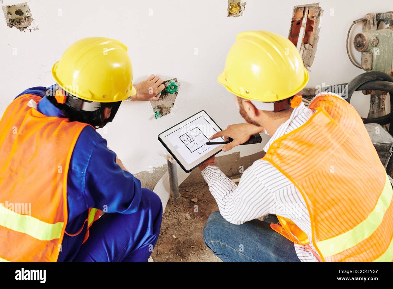 Builders checking plan of apartment when installing pipes in kitchen or ...