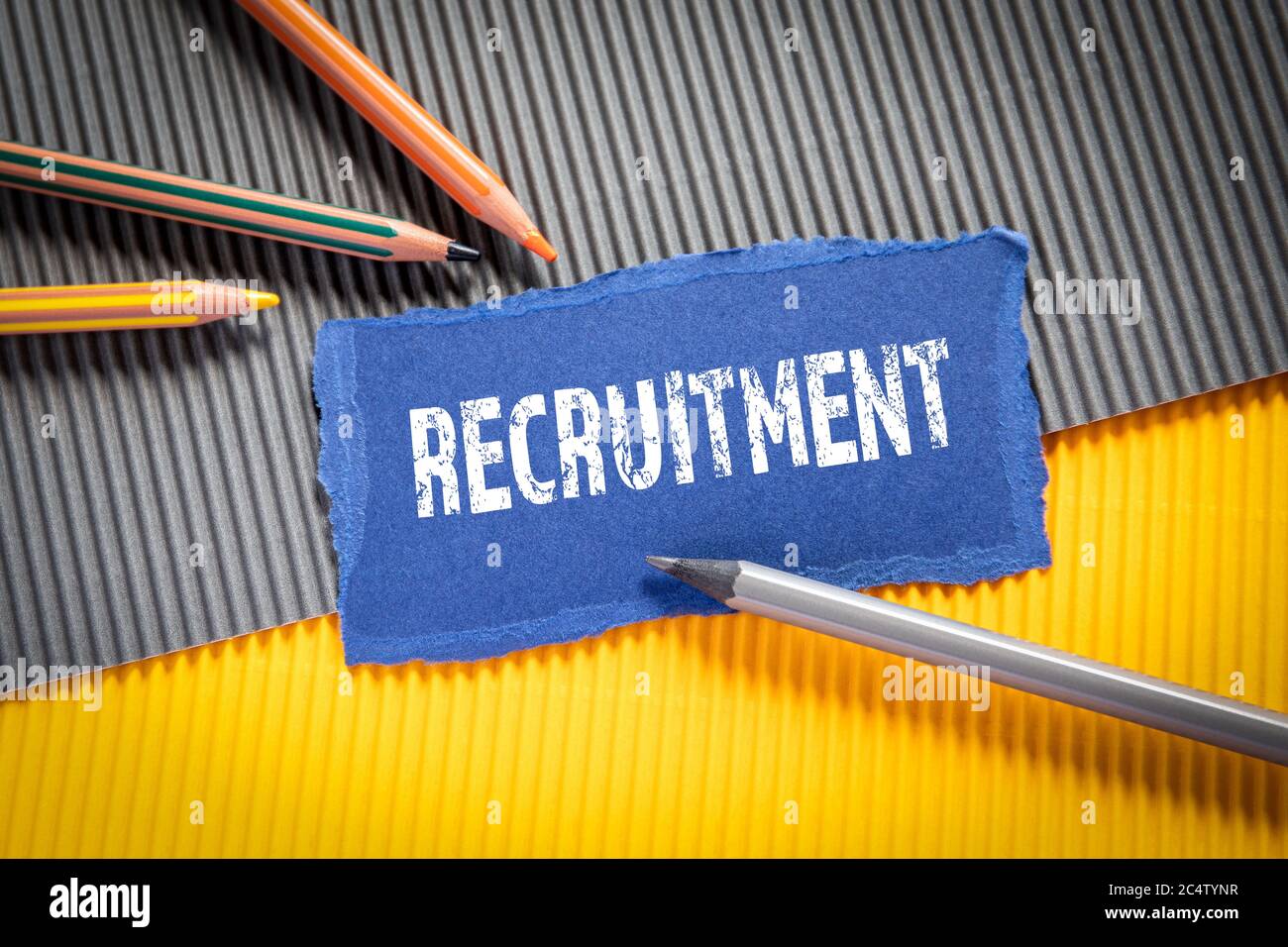 RECRUITMENT concept. Text on torn, colored paper on corrugated ...