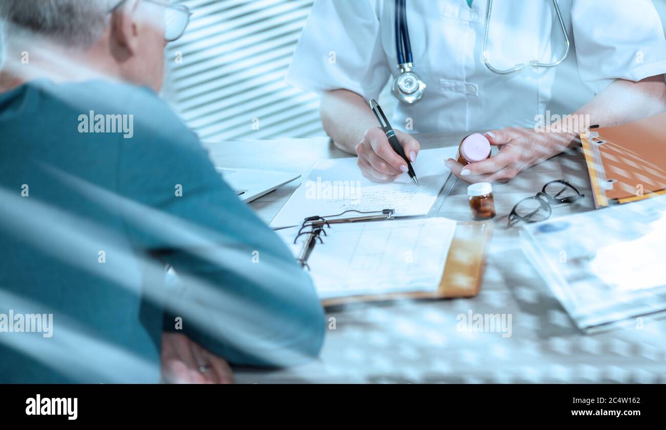 Female doctor writing prescription to her patient in medical office ...