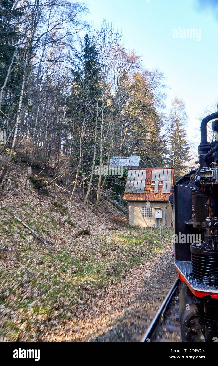 Old steam locomotive drives past a railway house with solar panels on ...