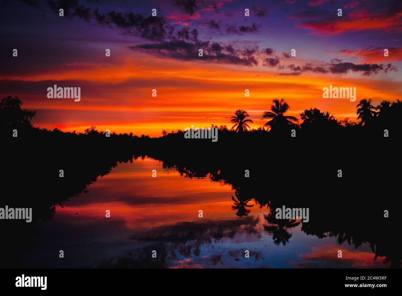 colorful sunset with clouds light rays over the river with reflections ...