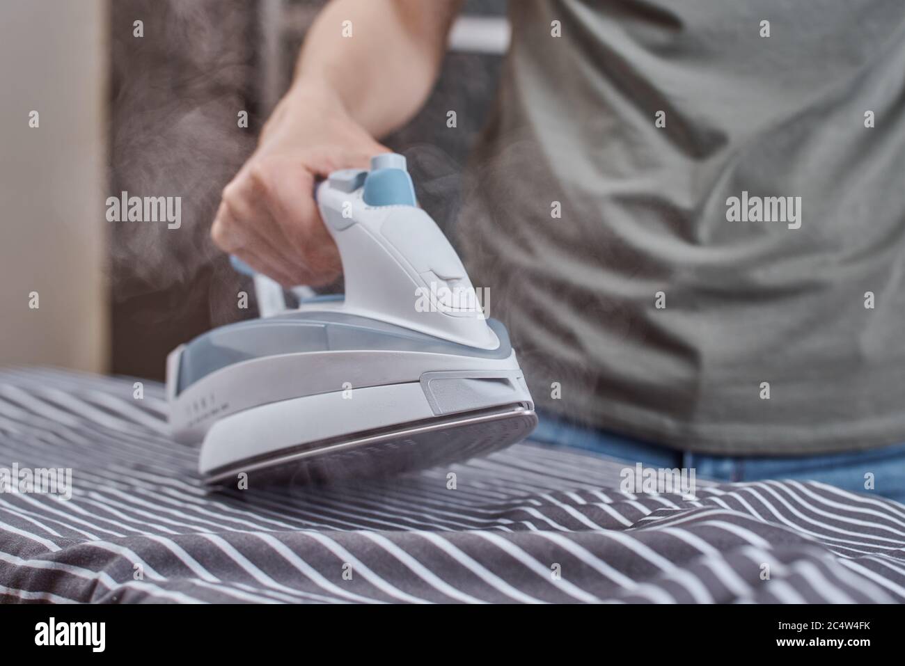Steam boost on modern iron. Woman ironing clothes with modern iron ...