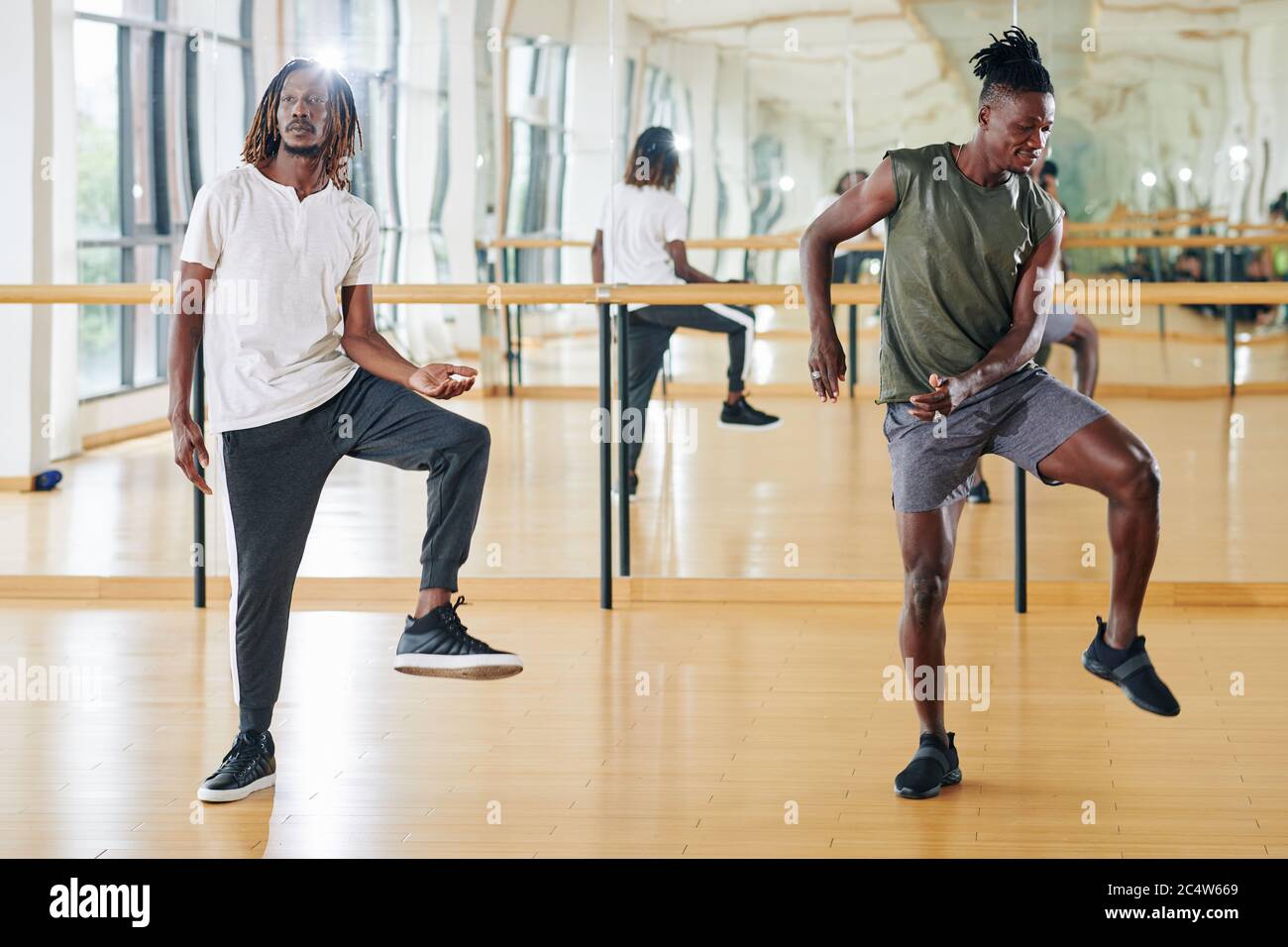 Young Black man attending dance class and repeating movement after the ...