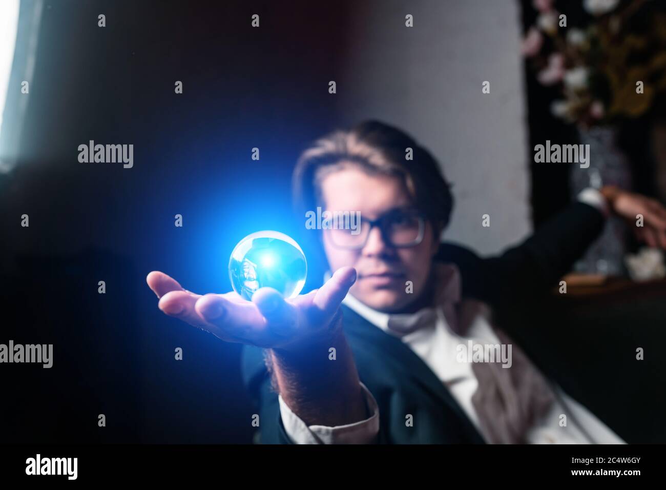 Young man holding a clear transparent crystal glass ball in their hand ...