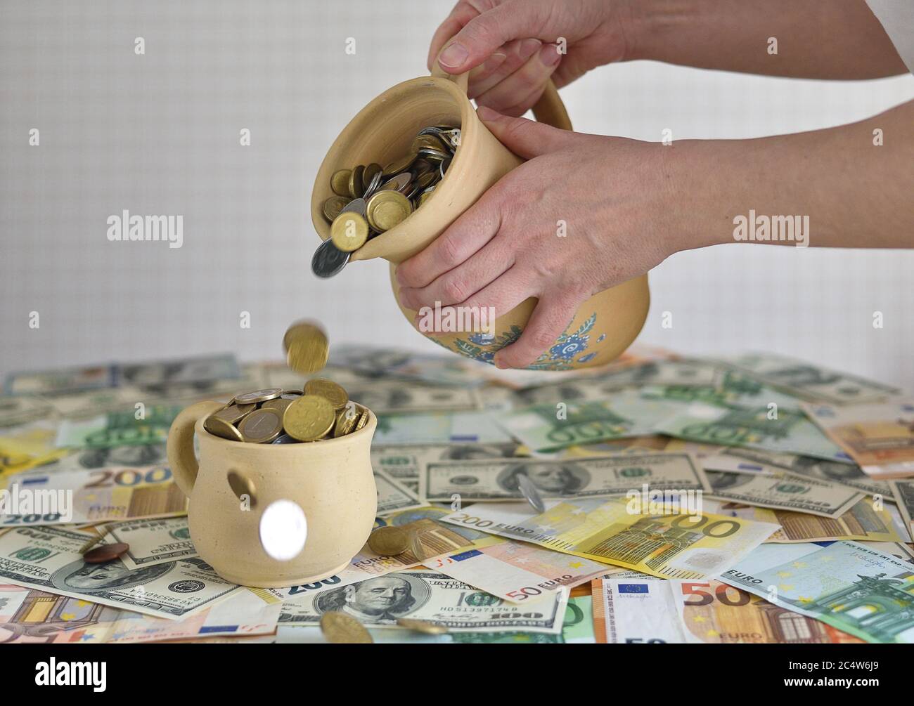 coins pour out of a jug into a cup. cup with money Stock Photo - Alamy