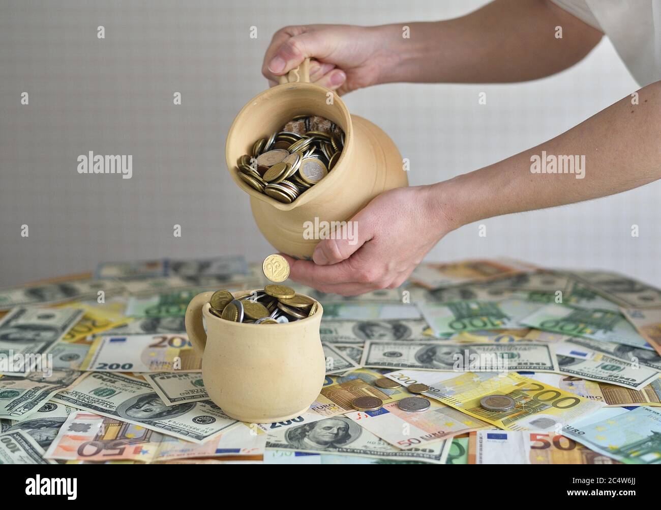 coins pour out of a jug into a cup. cup with money Stock Photo - Alamy