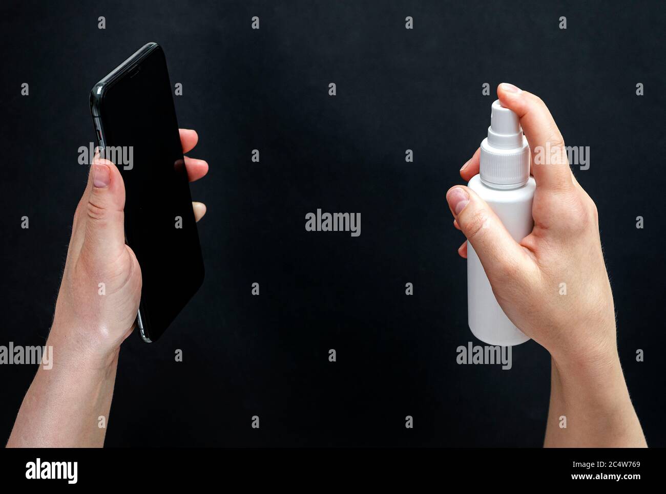 Woman hands spray alcohol sanitizer on her smart phone to protect from ...