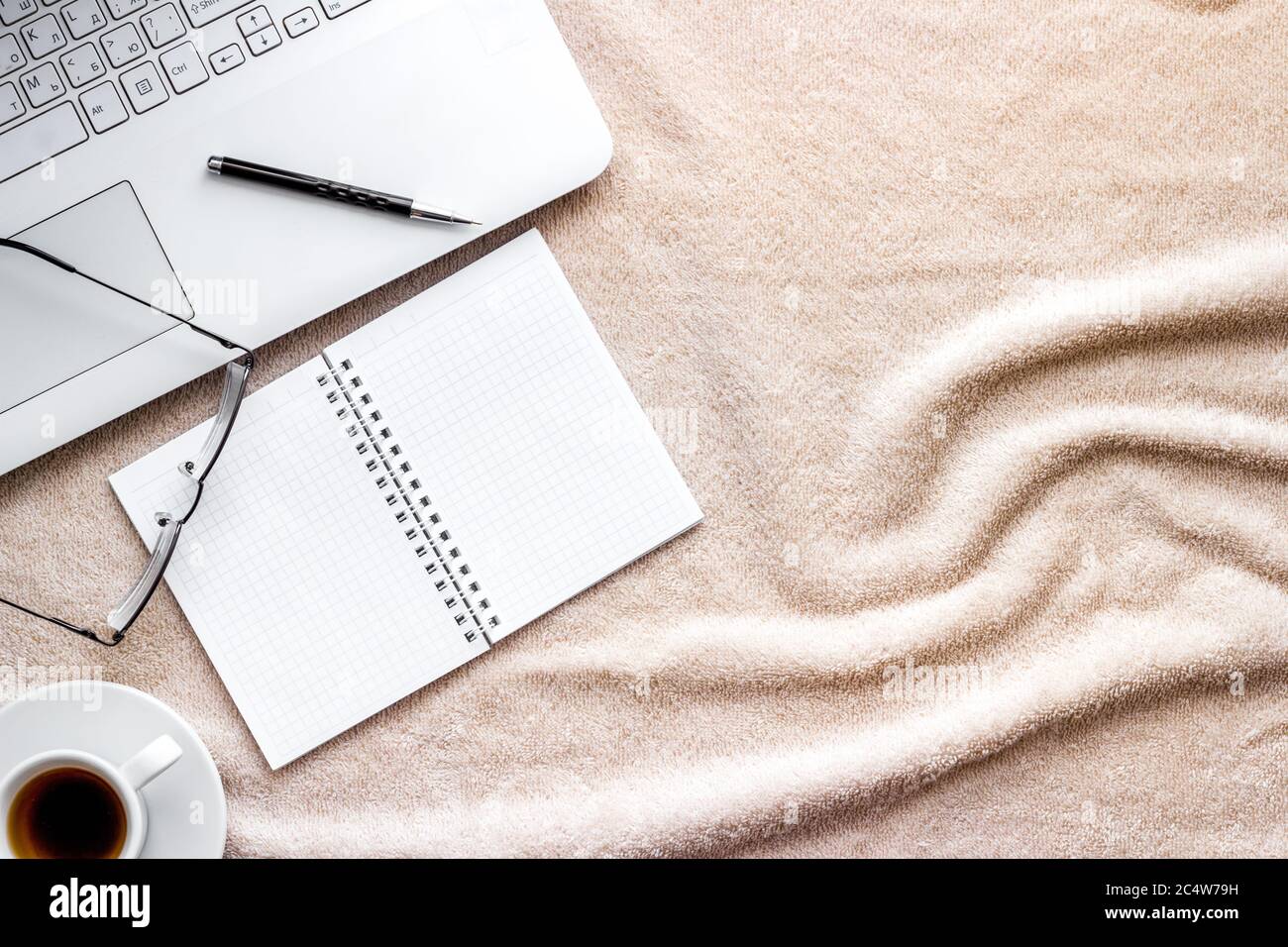Home office concept. Laptop, notebook on beige blanket form above copy ...