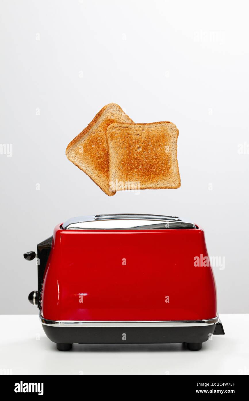 Two toasts jumping out of red toaster against white background Stock ...
