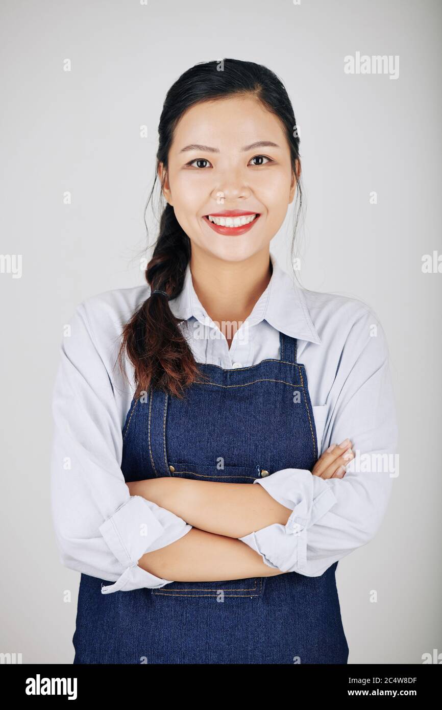 Portrait of young pretty Asian cafe waitress folding arms and smiling ...