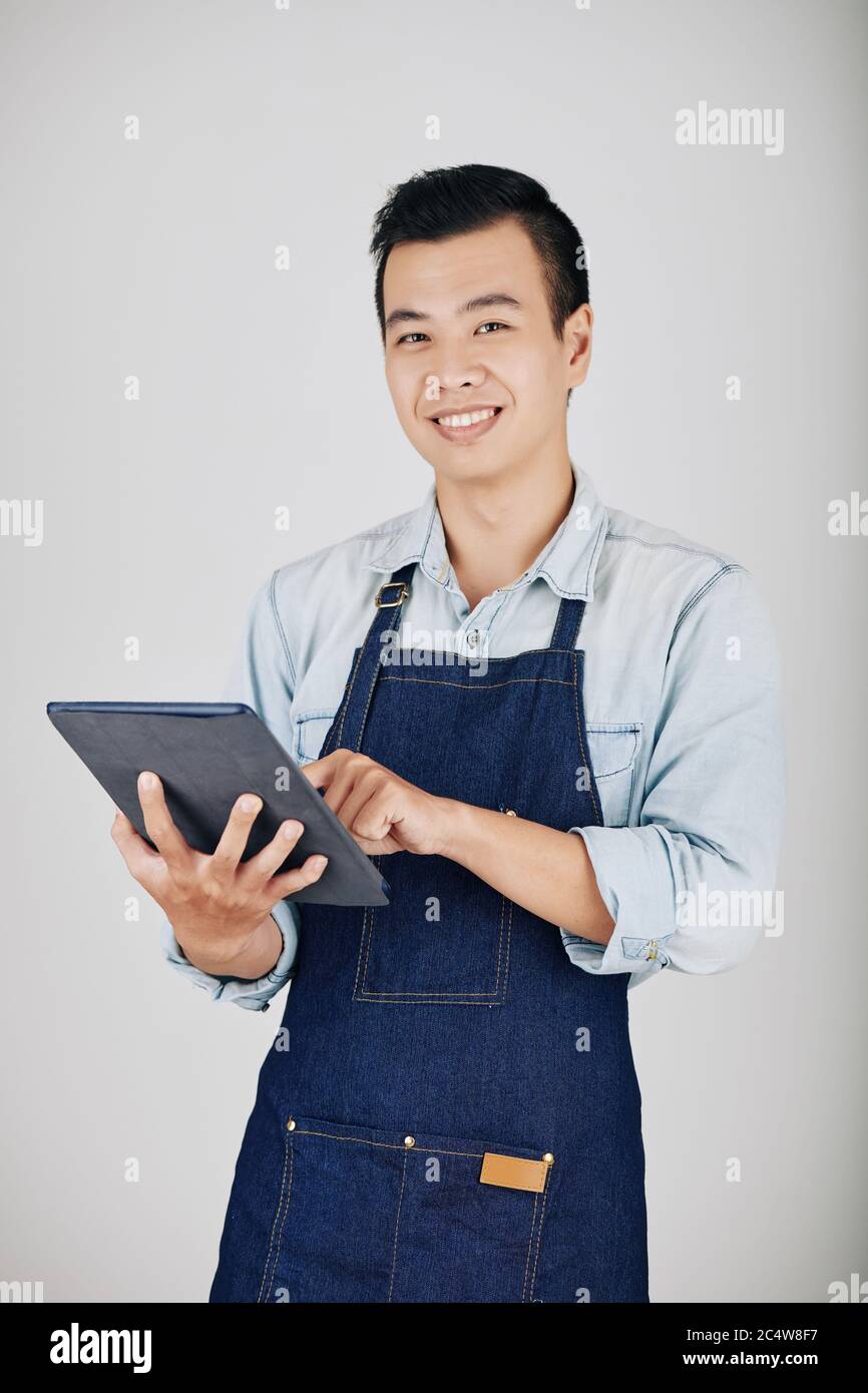 Studio shoot of smiling coffeeshop owner in denim apron using ...