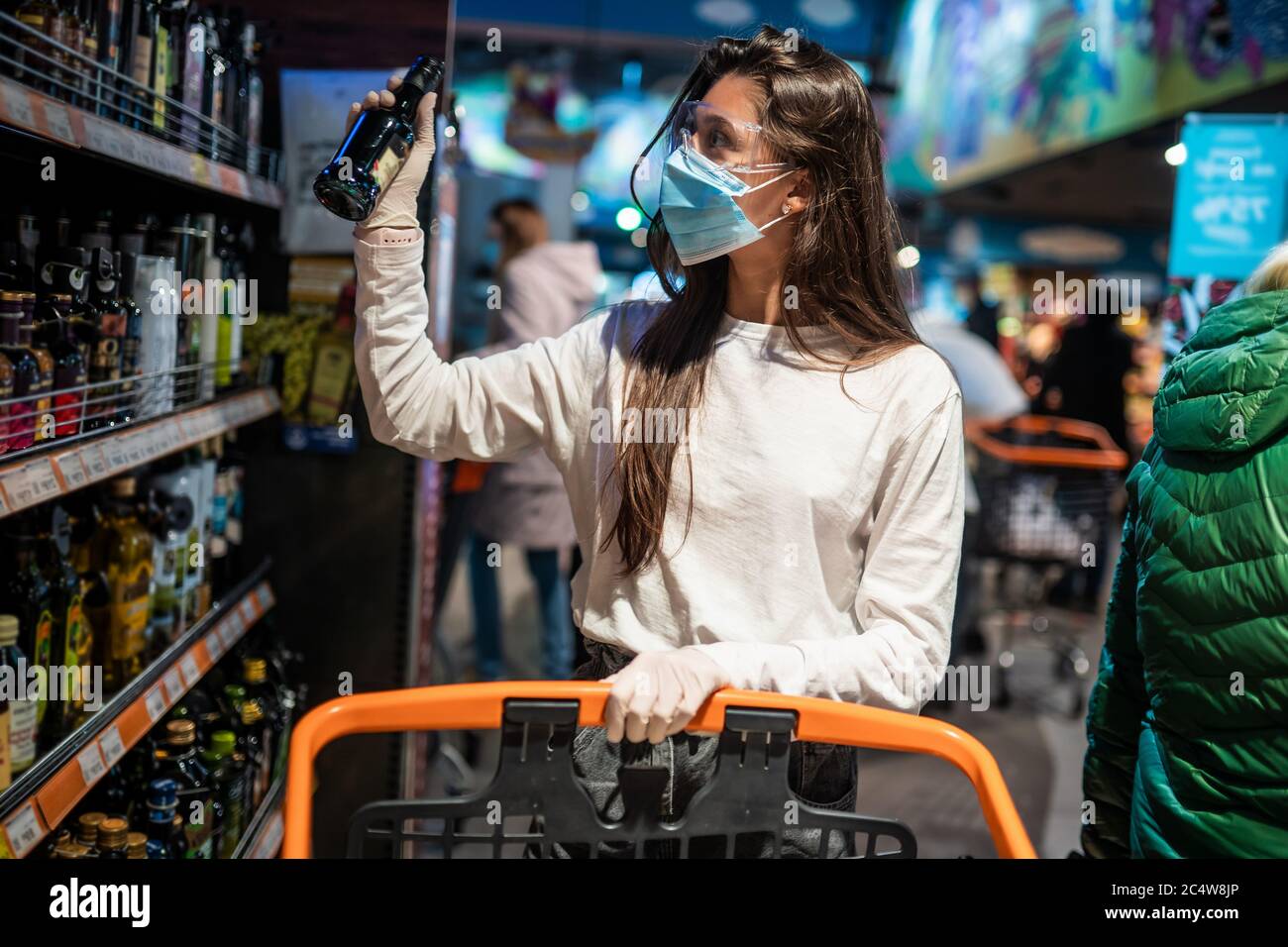 Woman with the surgical mask and the gloves is shopping in the ...