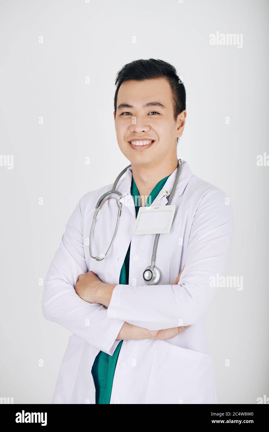 Portrait of smiling young Asian general practitioner in white labcoat ...