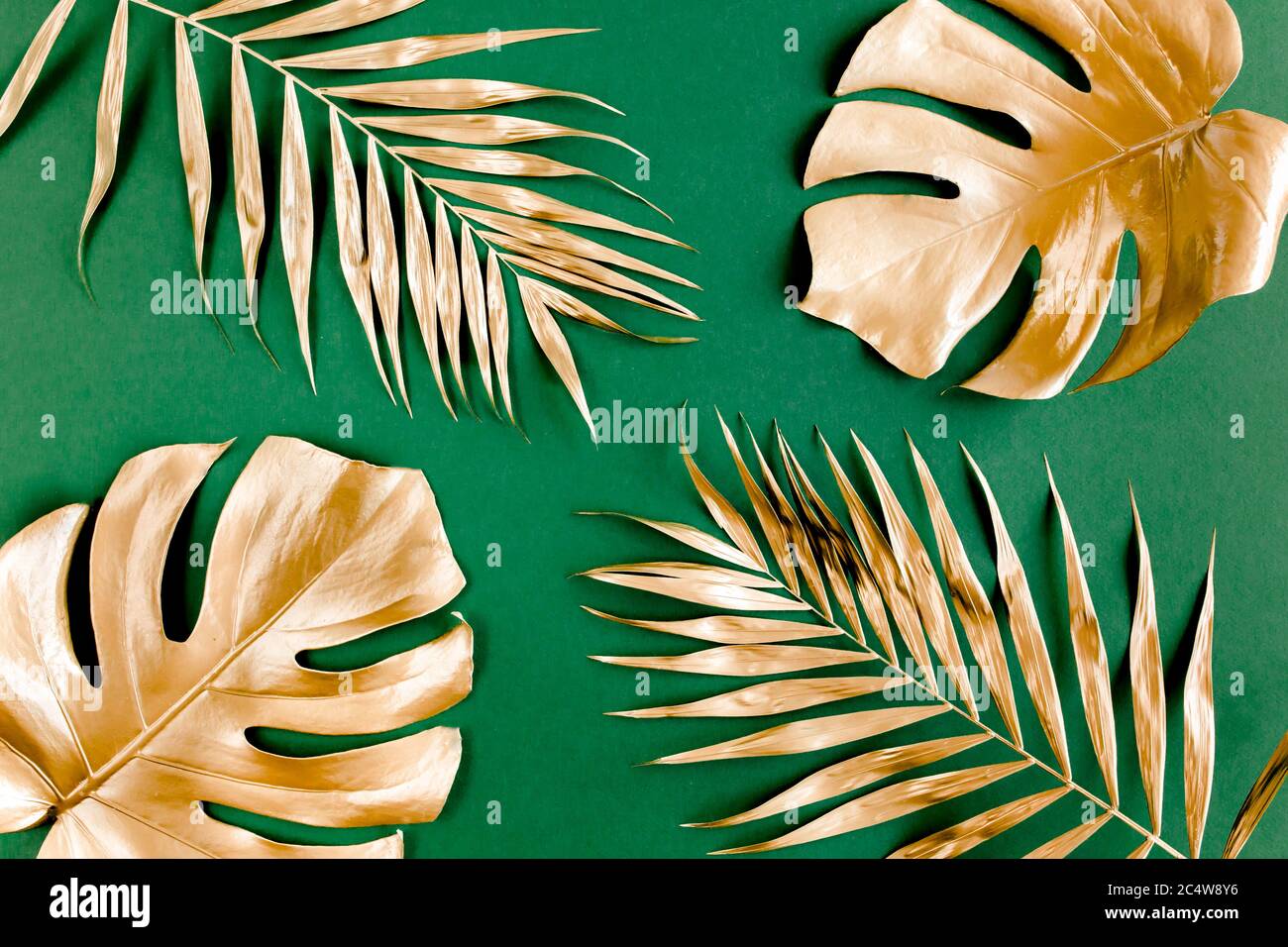 Gold tropical palm leaves Monstera on green background. Flat lay, top ...